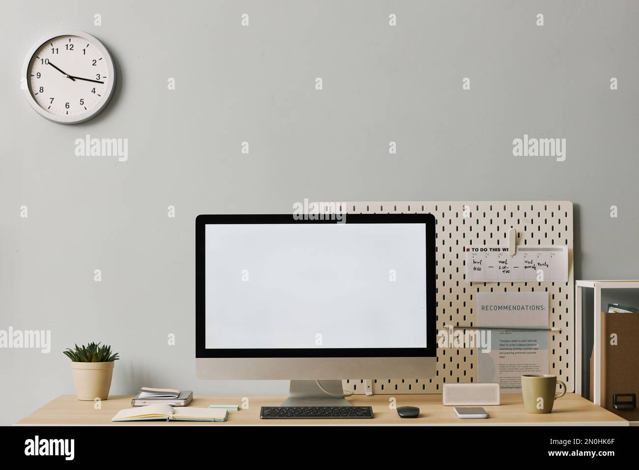 Background image of computer with blank white screen on desk in minimal home office setup with ...