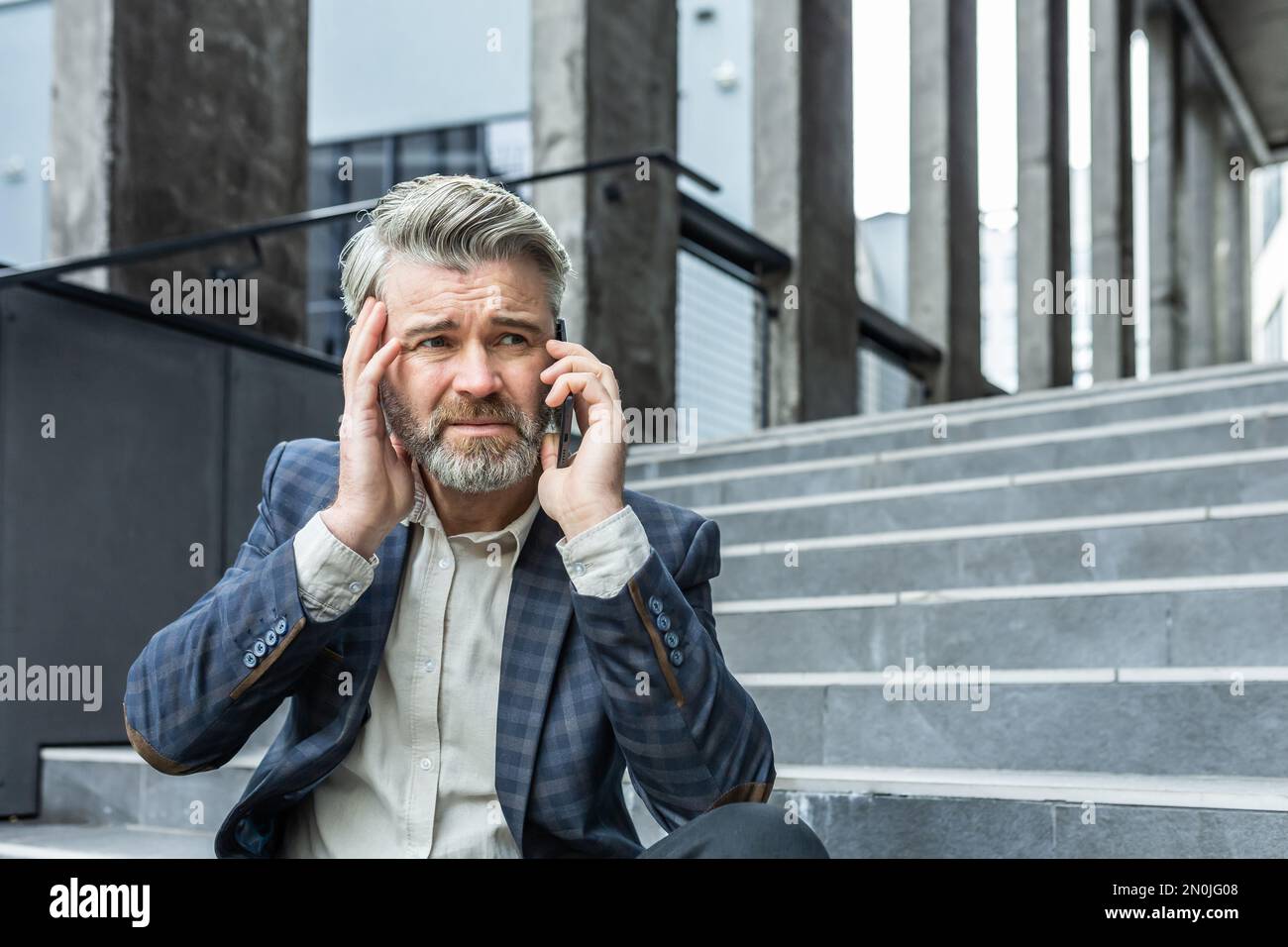 Upset and disappointed mature businessman sitting on stairs of office ...