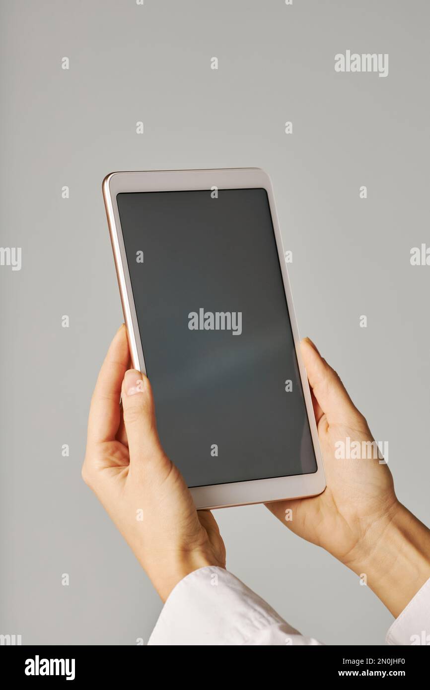 Vertical closeup of female hand holding tablet with blank screen ...