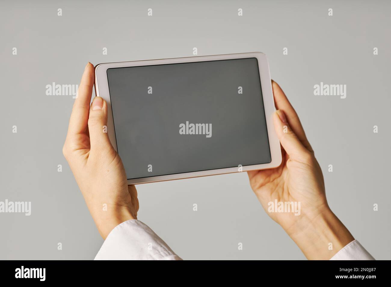 Close up of female hands holding tablet with blank screen against white ...