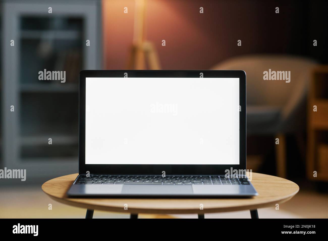 Background image of open laptop with white screen mockup in dim home ...