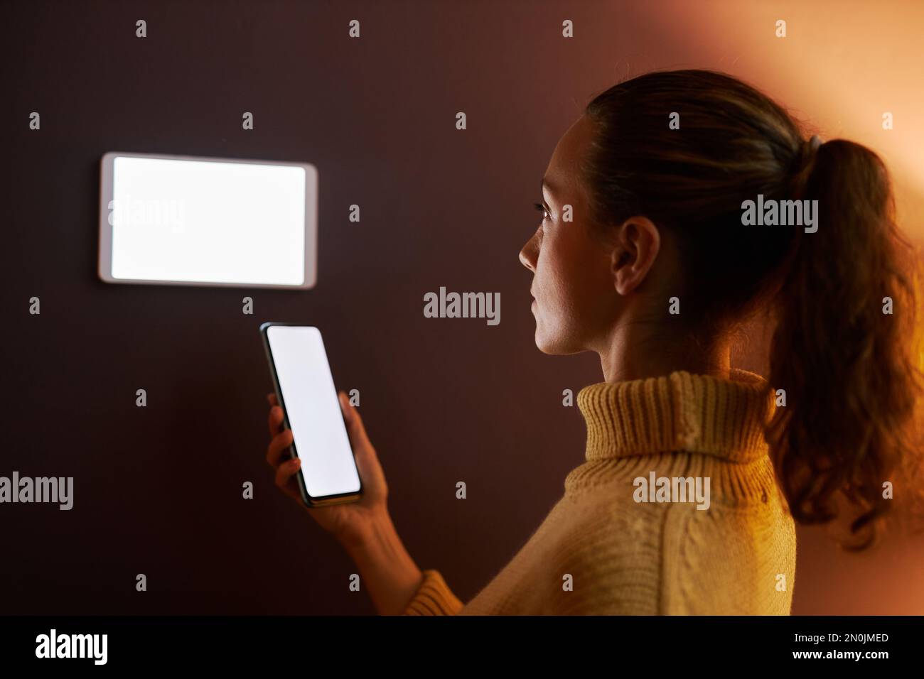 Side view portrait of young woman using digital smart home system with ...