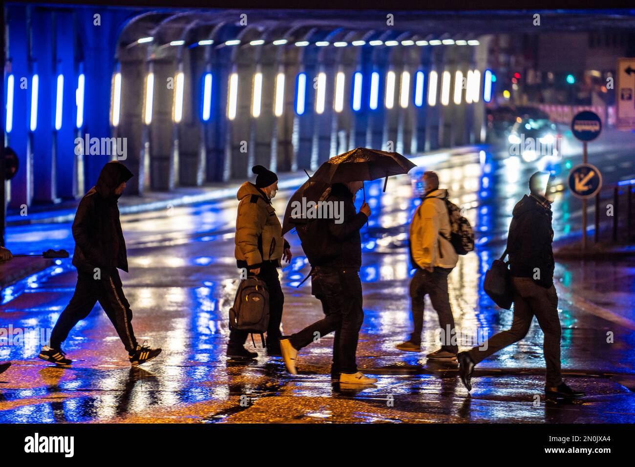 Illuminated subway at the main station, passers-by at a pedestrian crossing, rainy weather, city ...