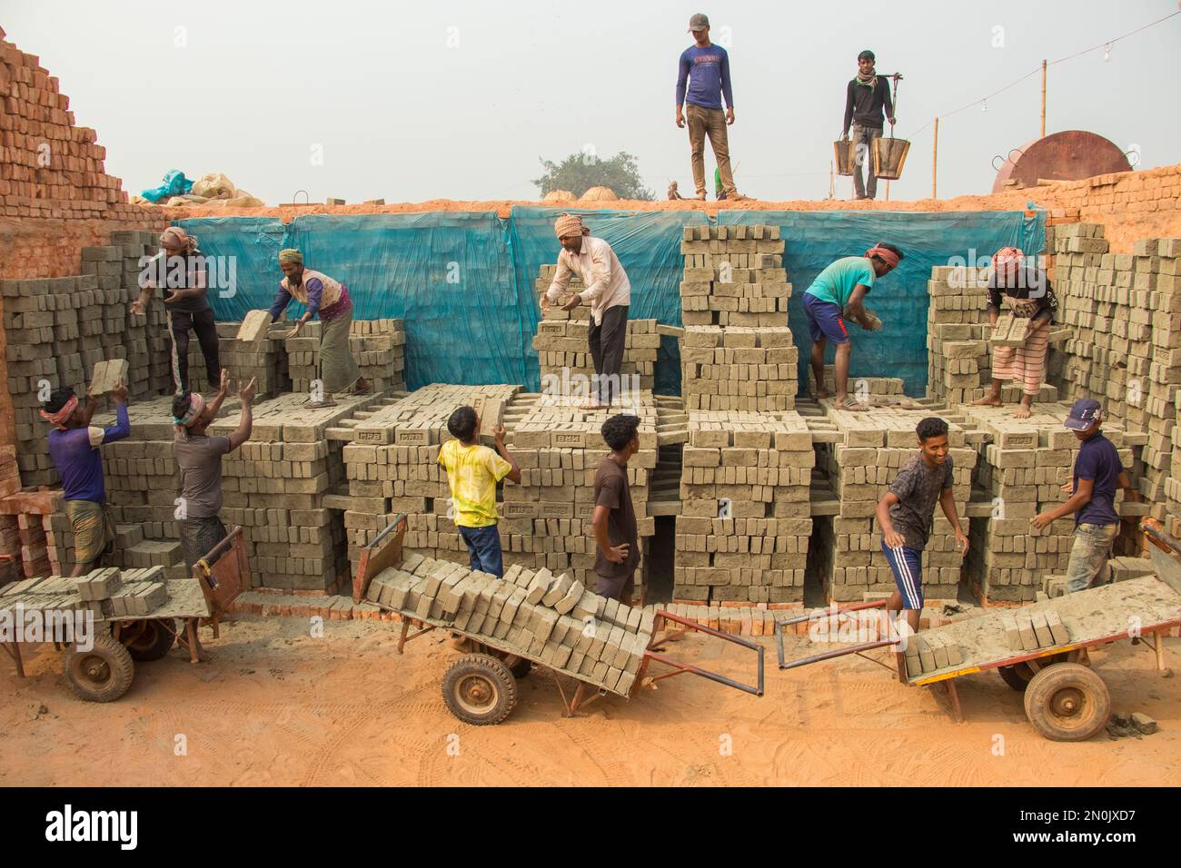 People are working hard in the brick field. This image was taken from ...
