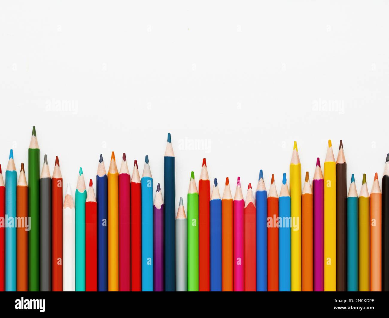 Row of colorful watercolor pencils. School supplies on light paper ...