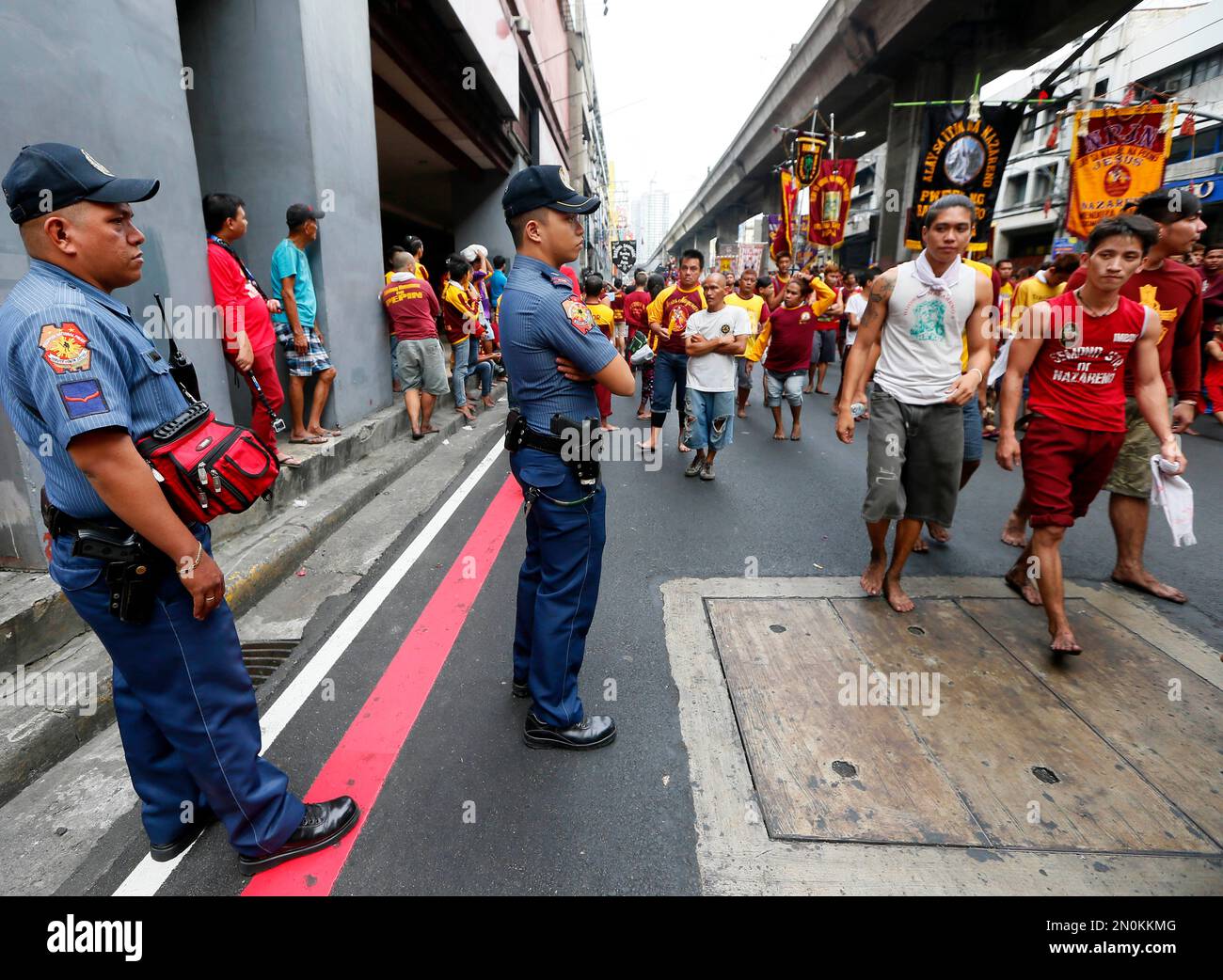 Police officers watch as barefoot Filipino Catholic devotees join a ...