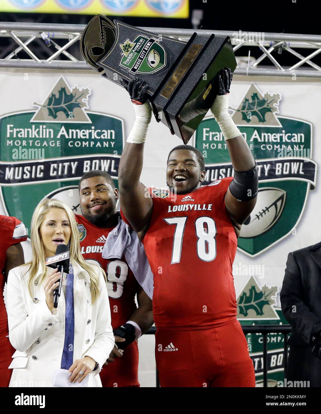 Louisville offensive tackle Aaron Epps raises the winner's trophy after beating Texas A&M 27-21 ...