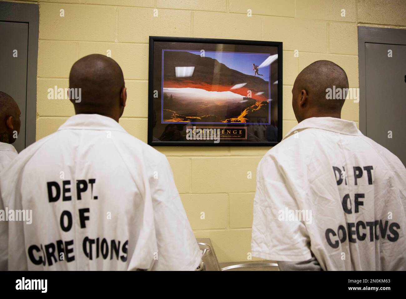 A motivational poster hangs on the wall as prisoners stand at attention ...