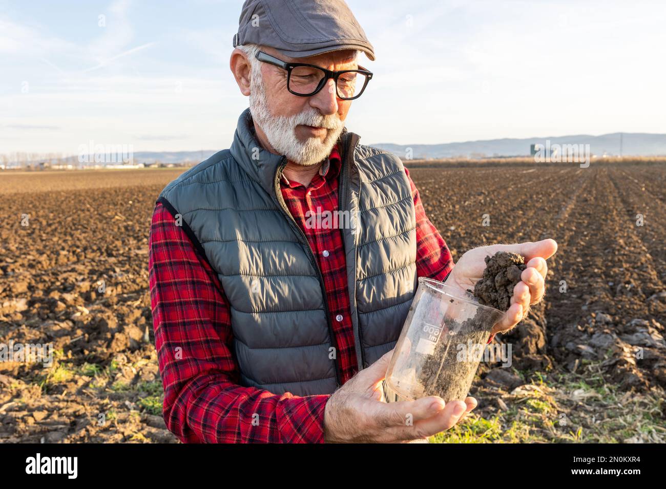 Mature farmer checking soil quality in field in autumn time Stock Photo ...