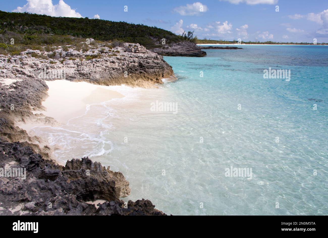 The scenic view of transparent waves and a tiny beach surrounded by ...