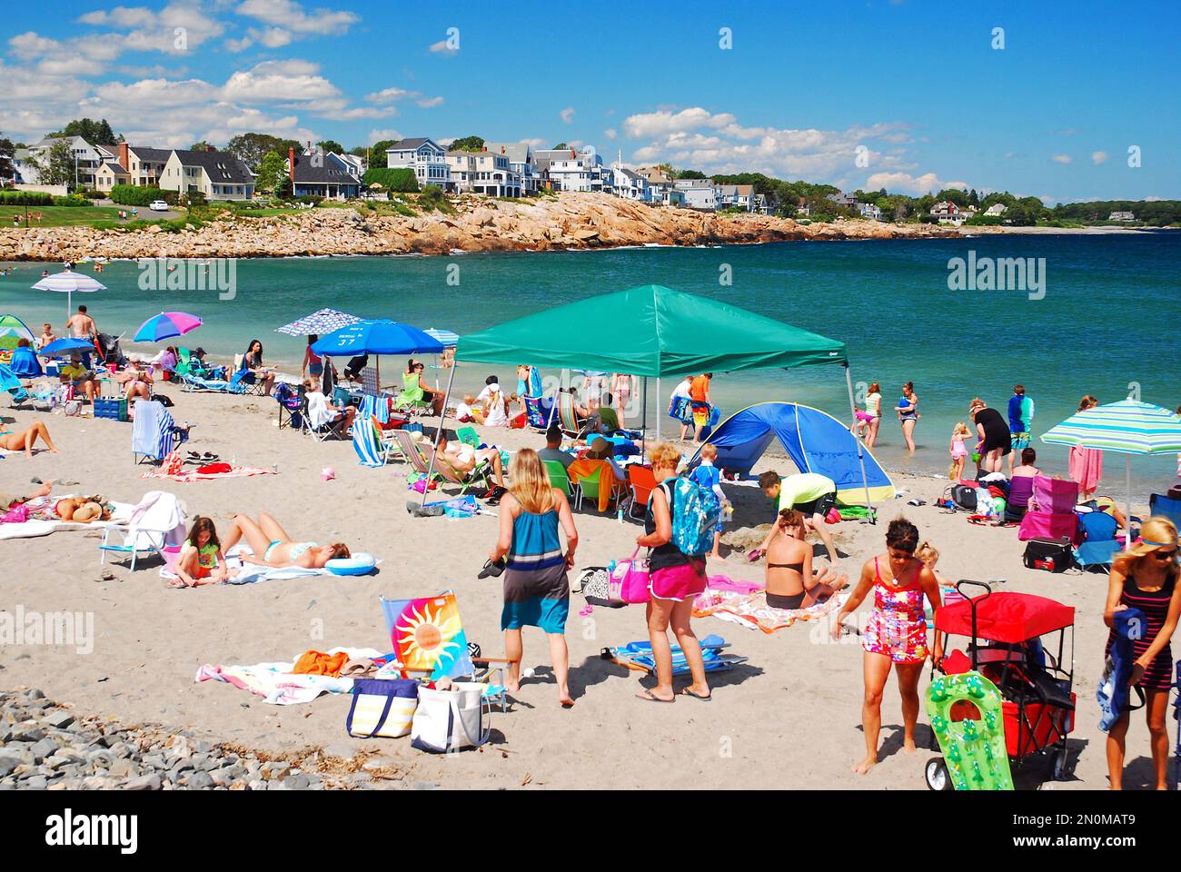 A crowd vies for valuable sand real estate on a small beach on the ...