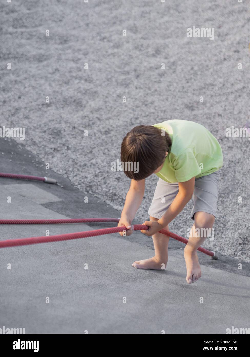 Boy climbes up a concrete slope of modern children's sports and ...