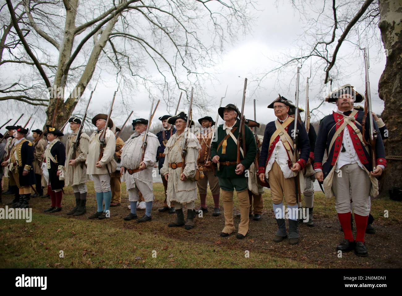 A group of Revolutionary War re-enactors stand at attention along the ...
