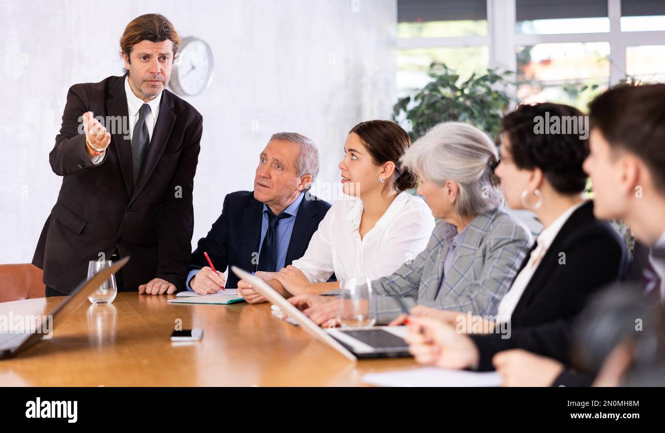 Dissatisfied male boss telling off office workers of different ages ...