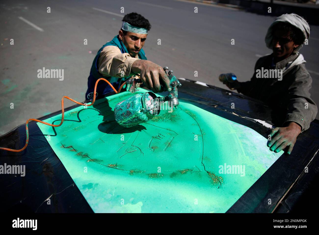 A man uses a stencil bearing the name of the Prophet Muhammad in Arabic ...