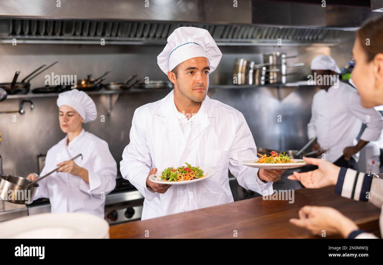 Service process in cafe - chef serves ready meals to visitors of modern ...