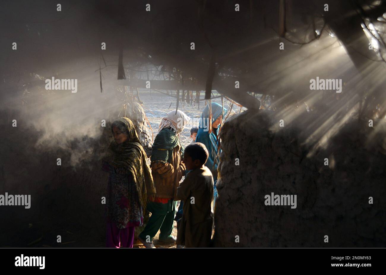 Afghan children watch as laborers produce sugar cane juice in a ...