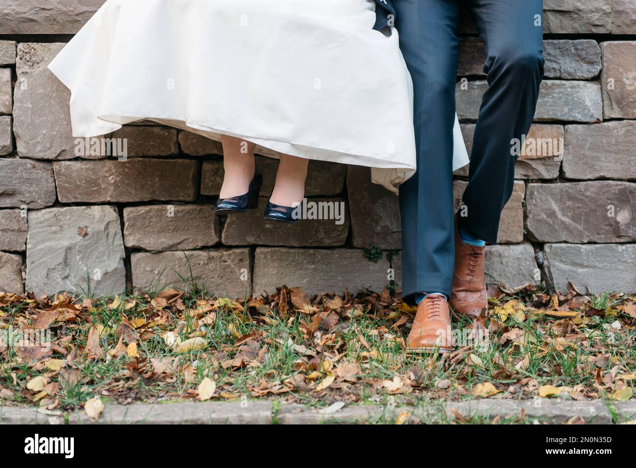 The legs of the bride and the groom sitting on a stone border Stock ...