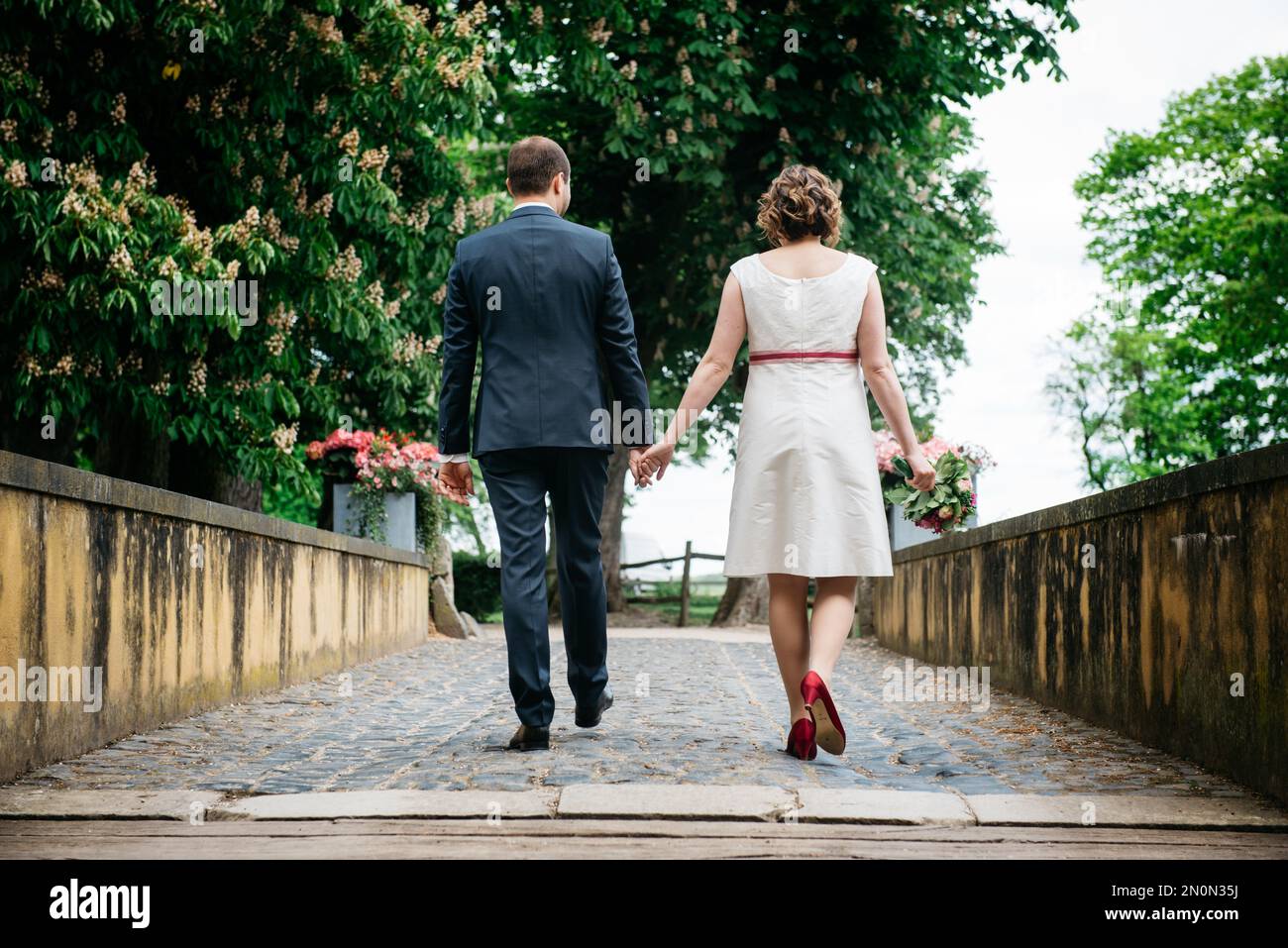 A back view of the bride and the groom walking in a park Stock Photo ...