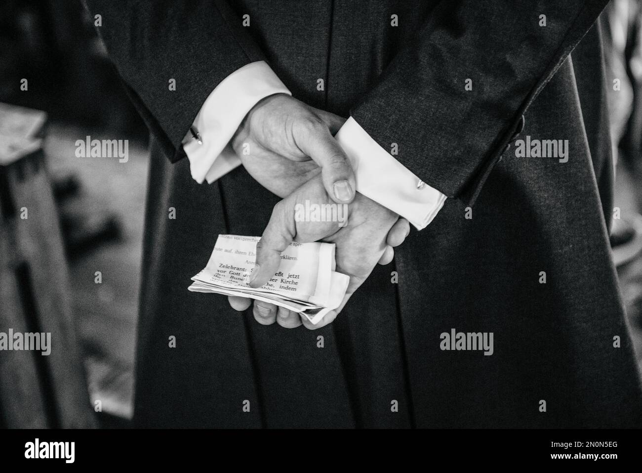 A greyscale back view of a person holding papers with notes behind his ...