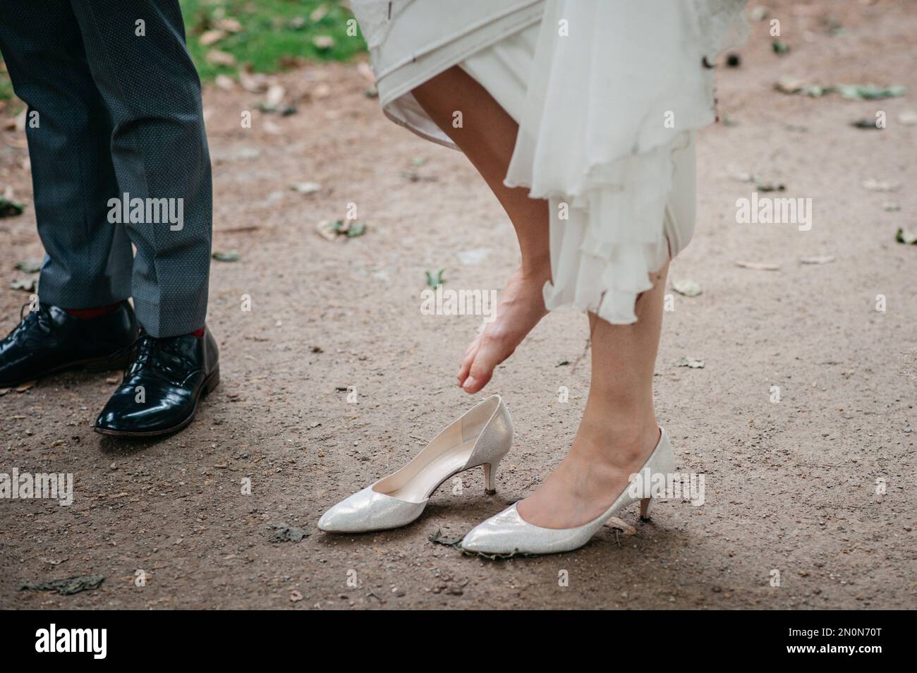 The bride taking her shoe off while walking with the groom Stock Photo ...