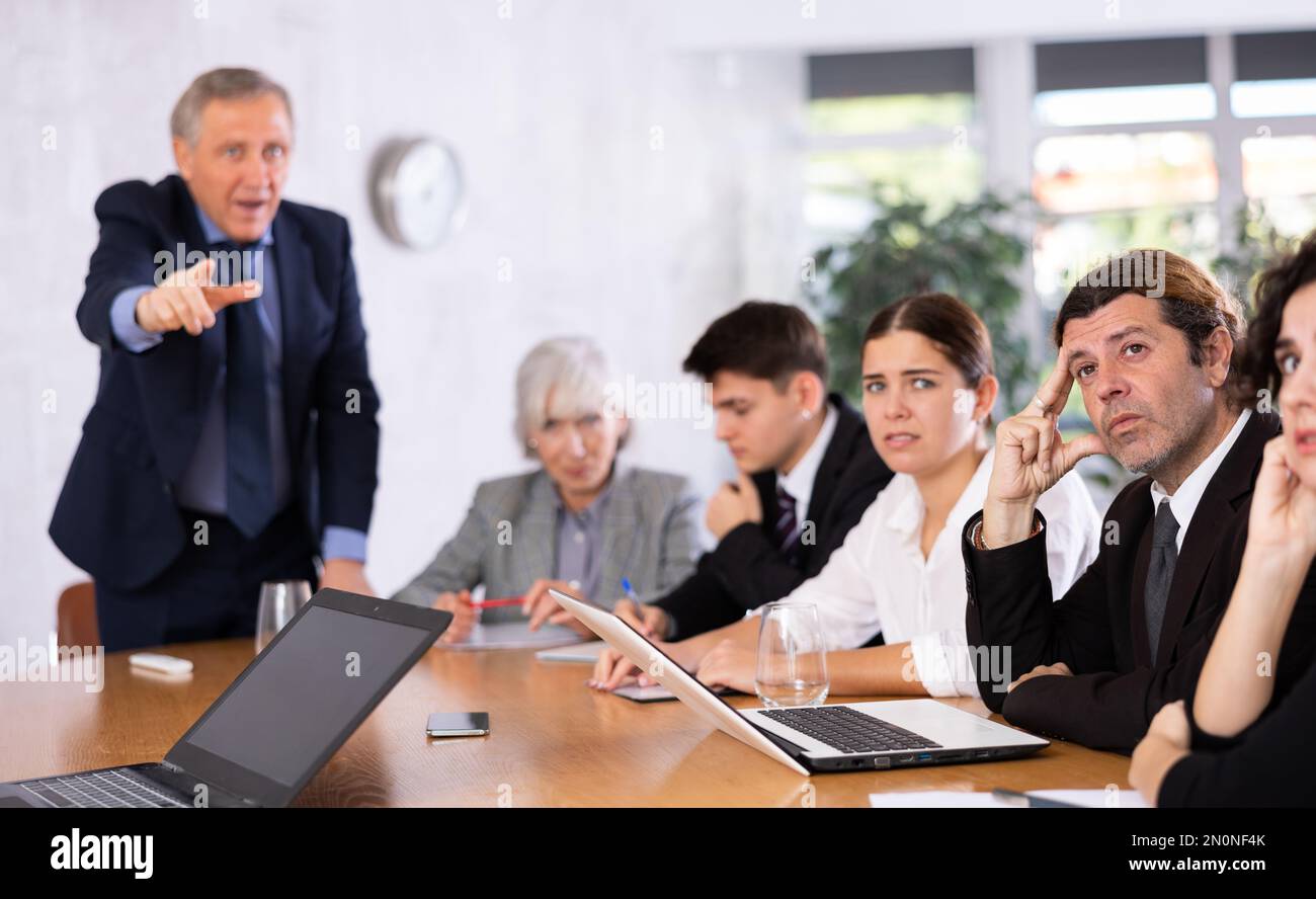 Angry male boss reprehending colleagues on meeting in office Stock ...