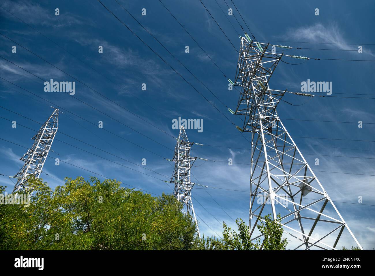 Tower with high-voltage energy transmission wires against the blue sky ...
