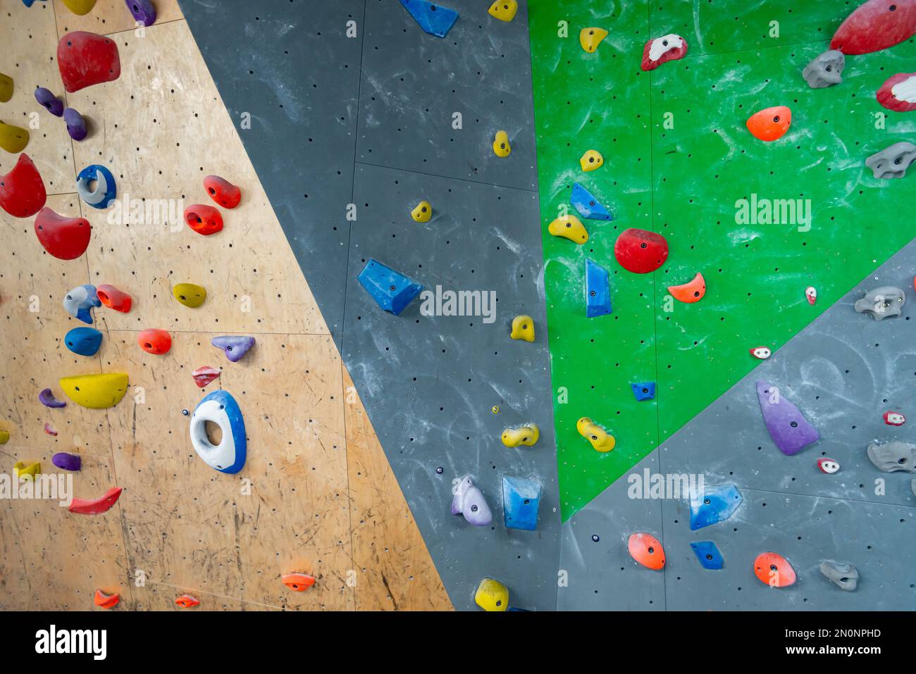 Multicoloured climbing wall holds grips of various shapes on grey and ...