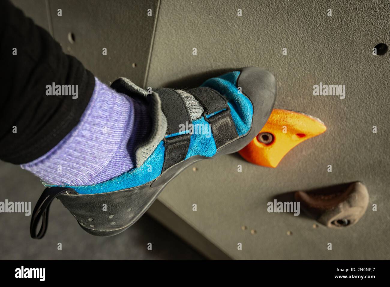 Close up of foot wearing indoor climbing wall shoe placed on orange ...