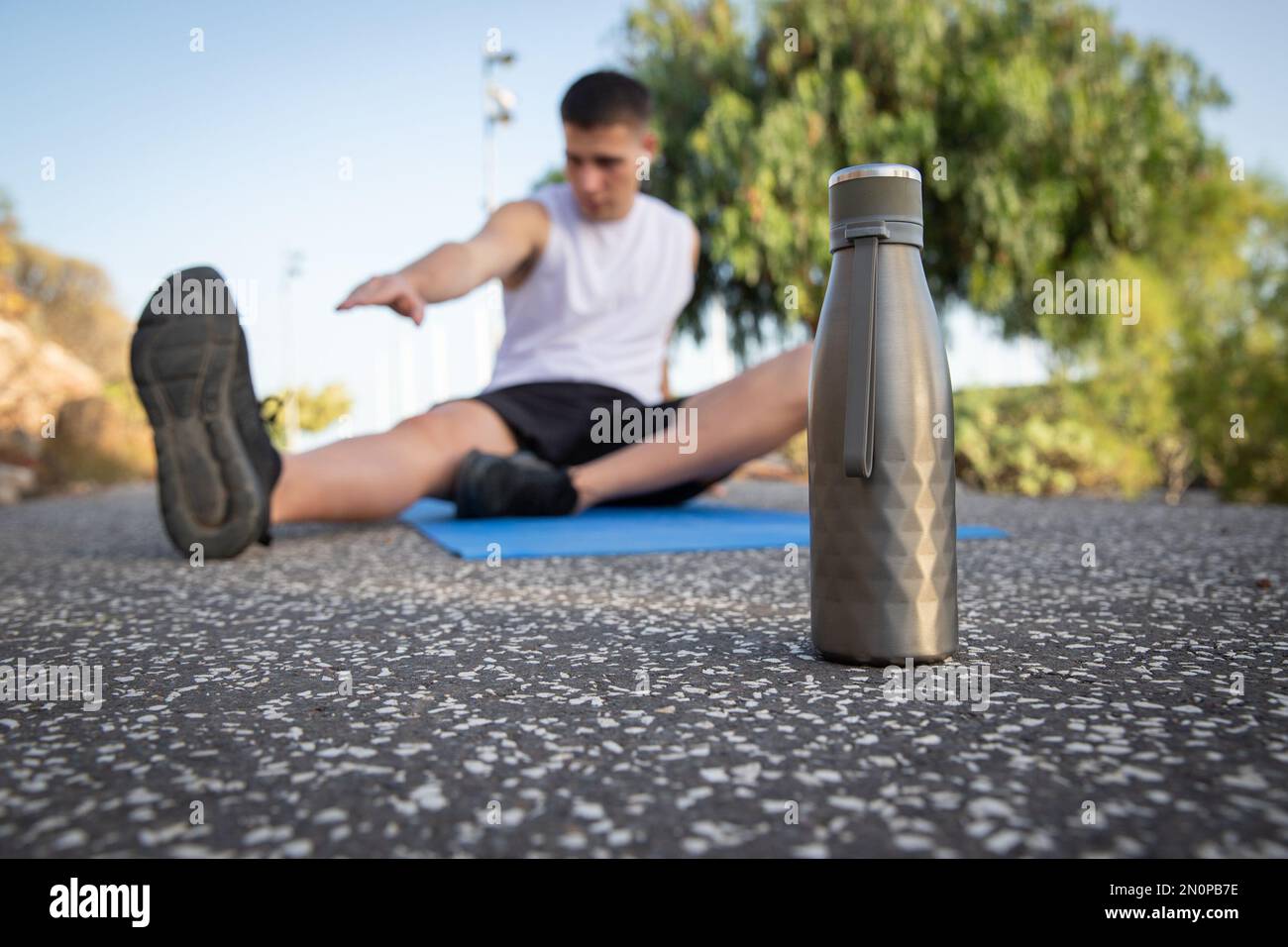 Closeup of water bottle with athlete behind stretching, hydration ...