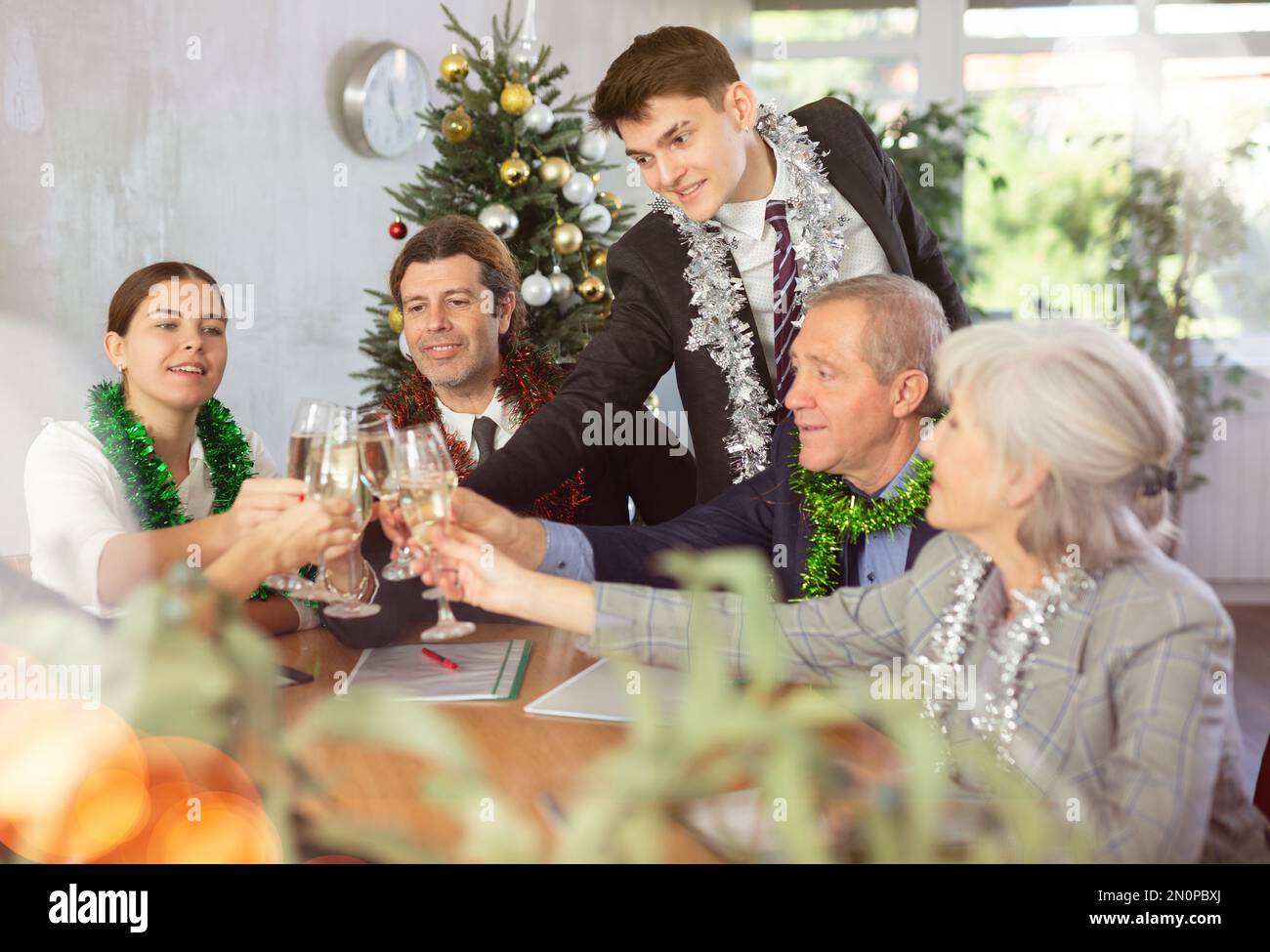 Cheerful young, adult, old office workers with glasses of champagne ...