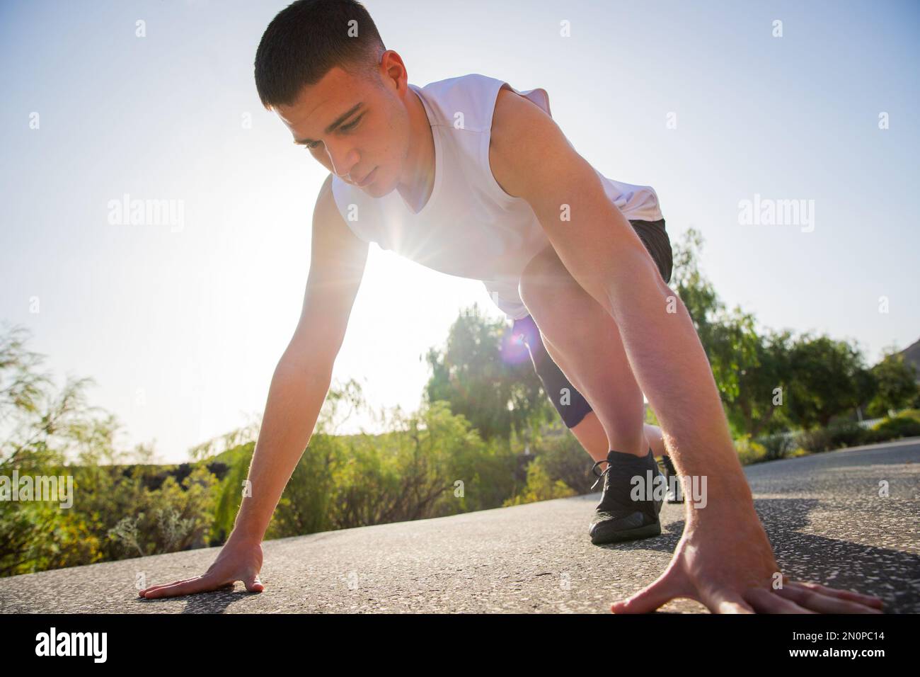 A runner in starting position during a workout, wellness and outdoor ...