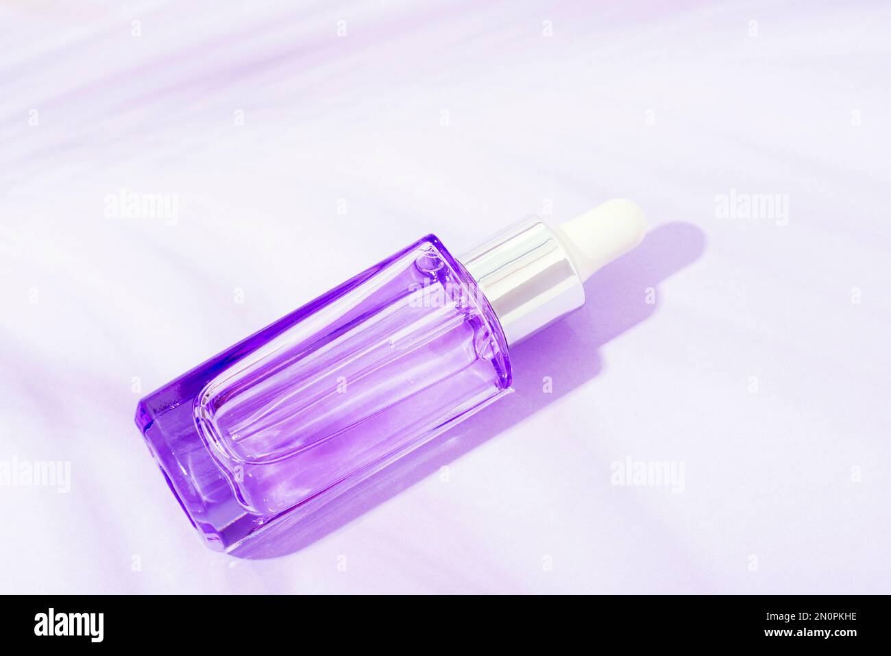 Purple cosmetic face serum bottle on the background with palm leaf ...