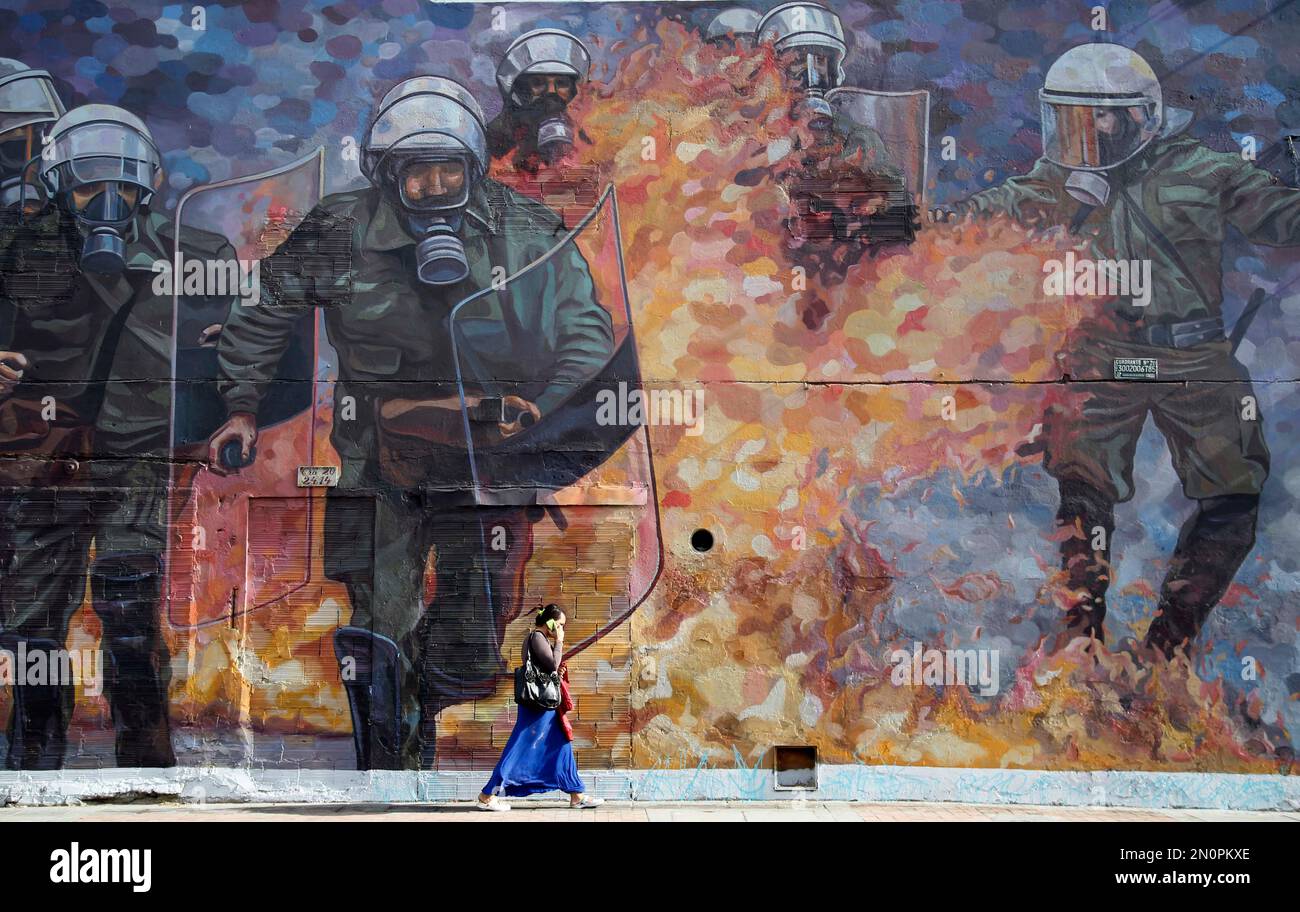 A woman walks past a mural depicting a scene of anti-riot police in ...