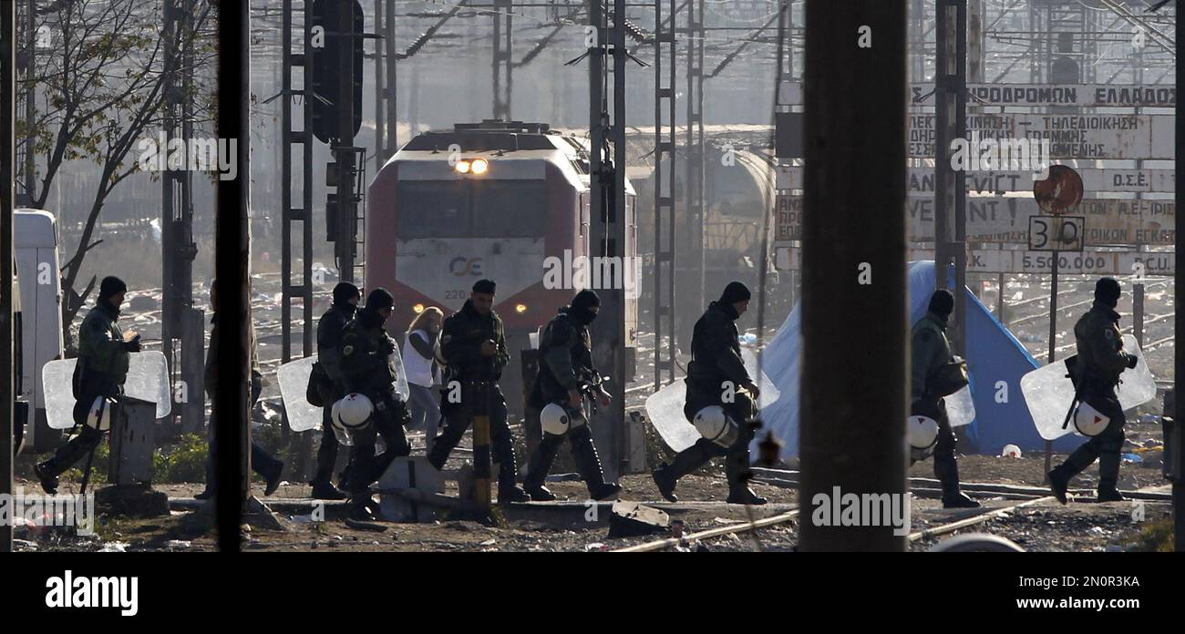 A locomotive heads towards Macedonia, as Greek riot police officers ...