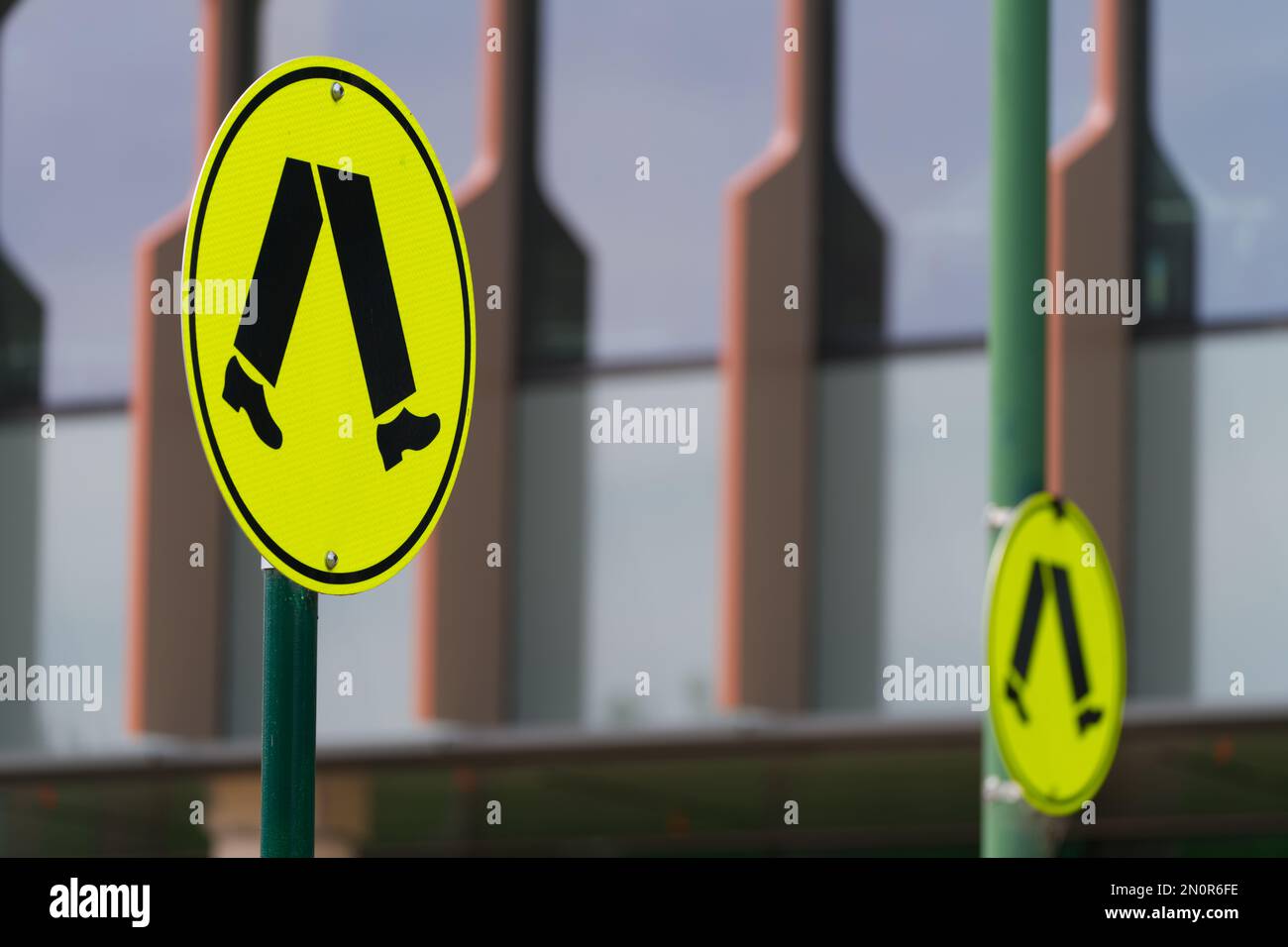 Yellow pedestrian crossing sign post isolated against an abstract ...