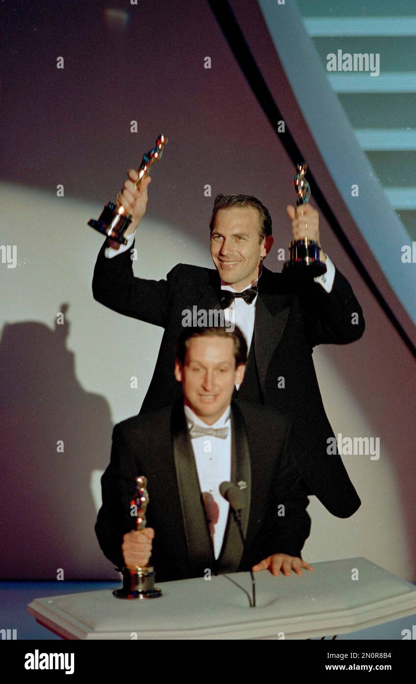 Actor Kevin Costner holds up two Oscars as co-producer Jim Wilson ...