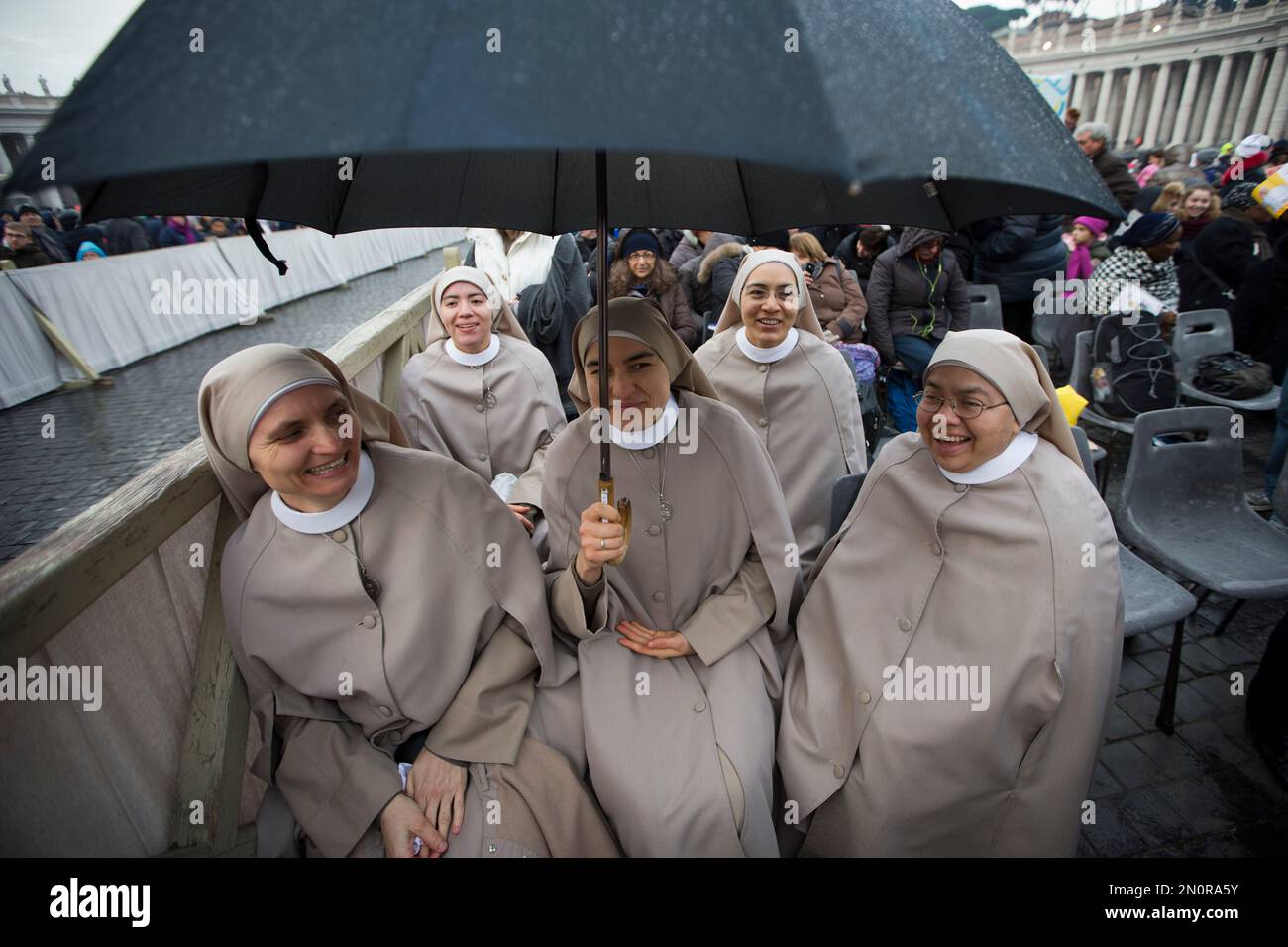 Nuns shelter themselves from the rain as they wait for Pope Francis to ...