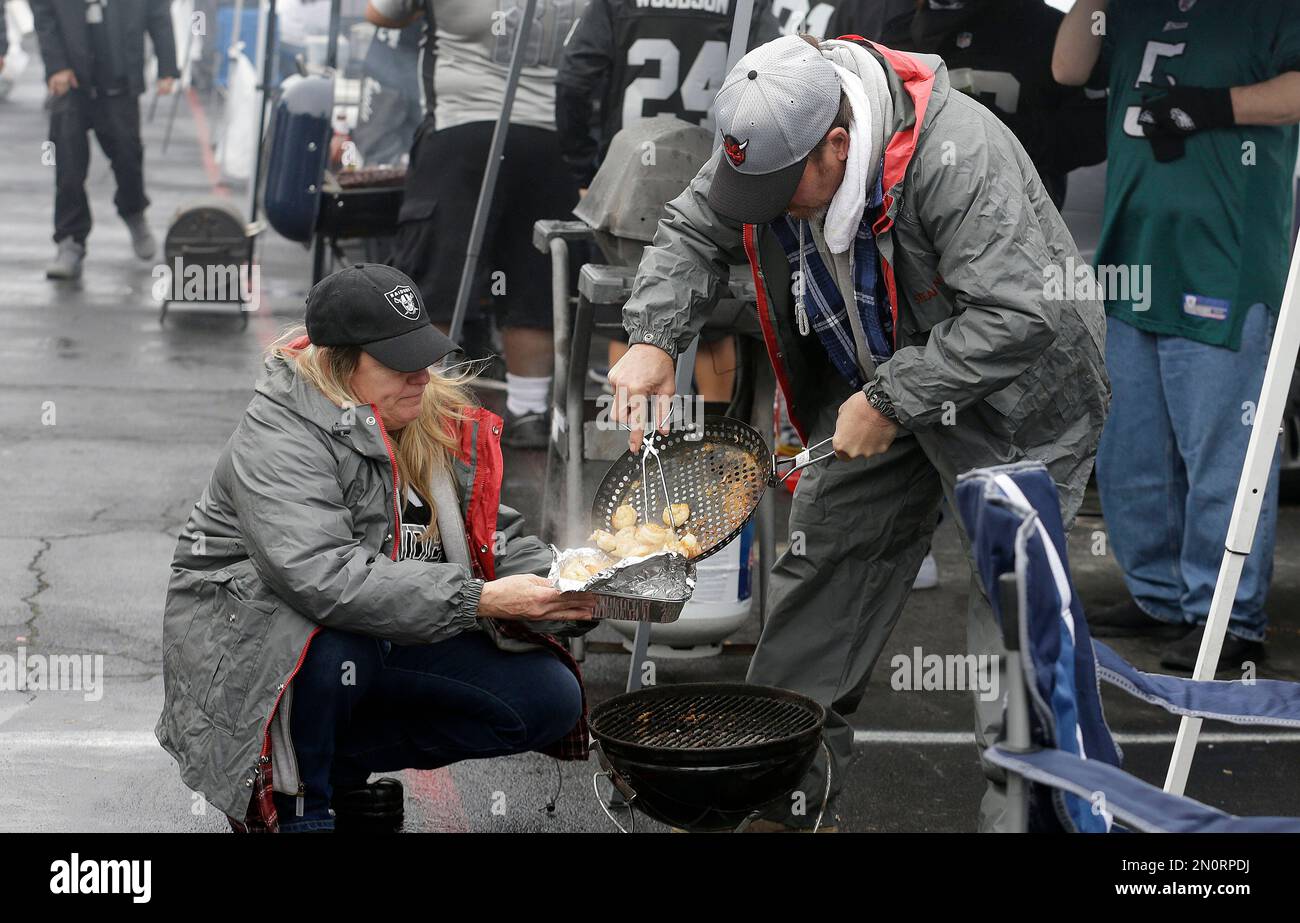 Fans cook while tailgating in the O.co Coliseum parking lot before an ...