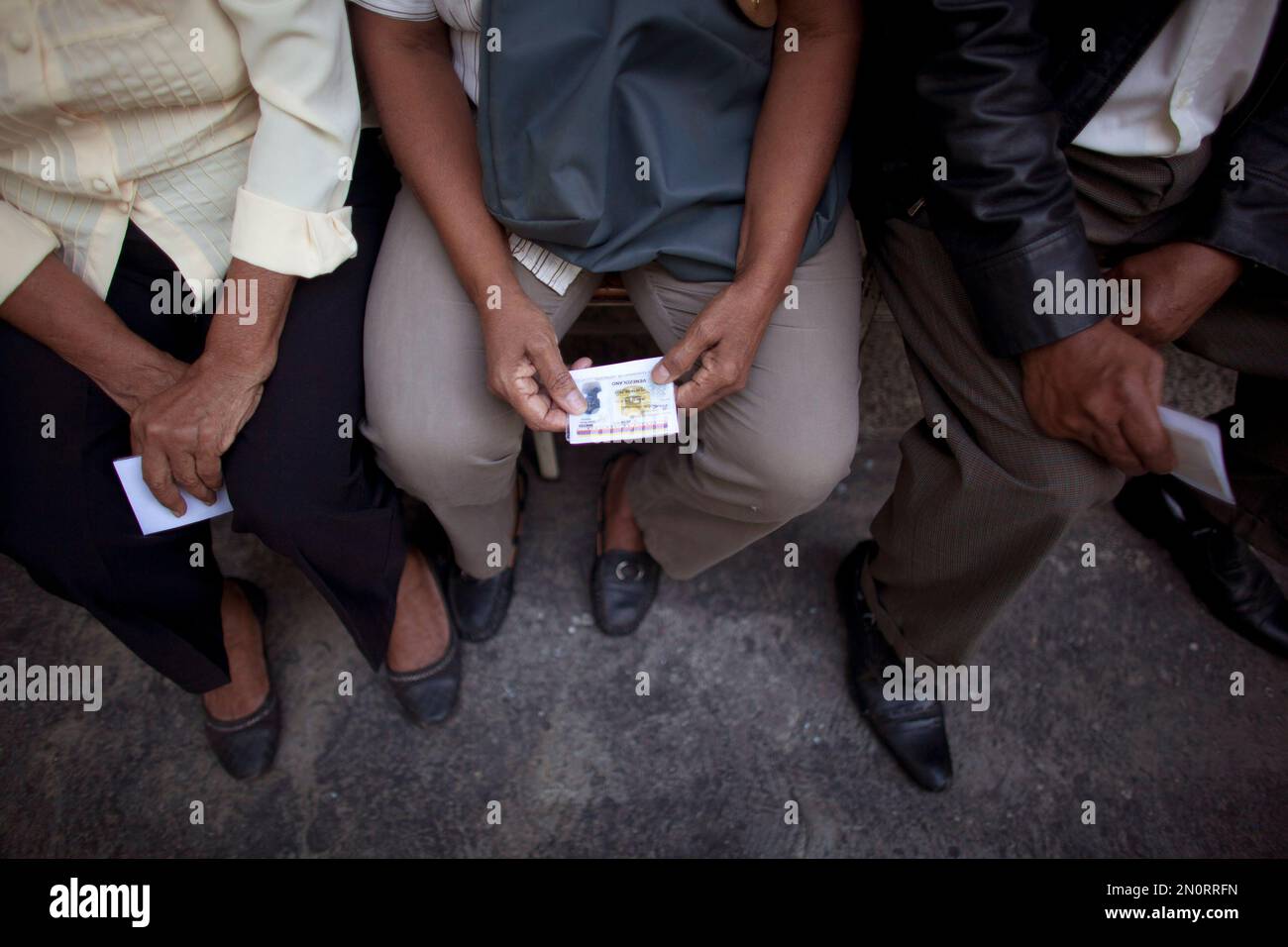 People hold their national identification cards as they wait to vote at ...