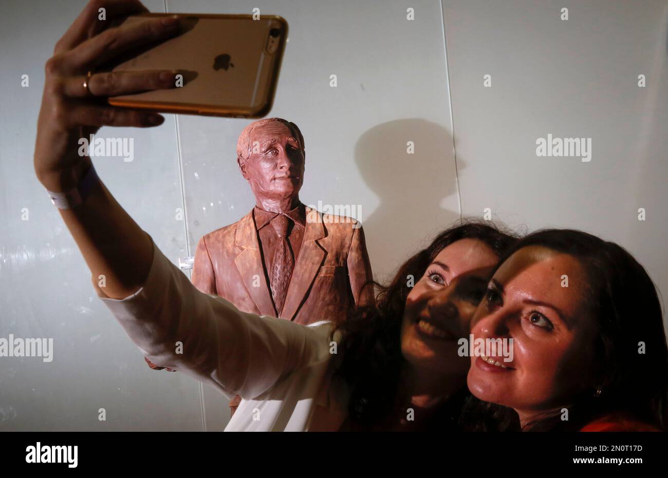 Visitors take a selfie with a chocolate statue of Russian President ...