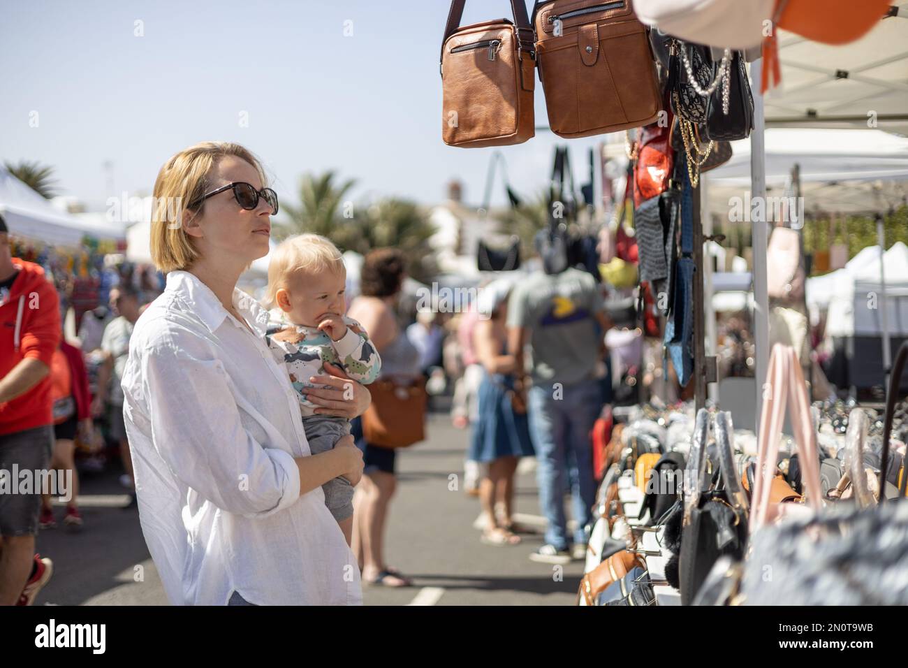 Mother hoding his infant baby boy child whilechecing items at sunday ...
