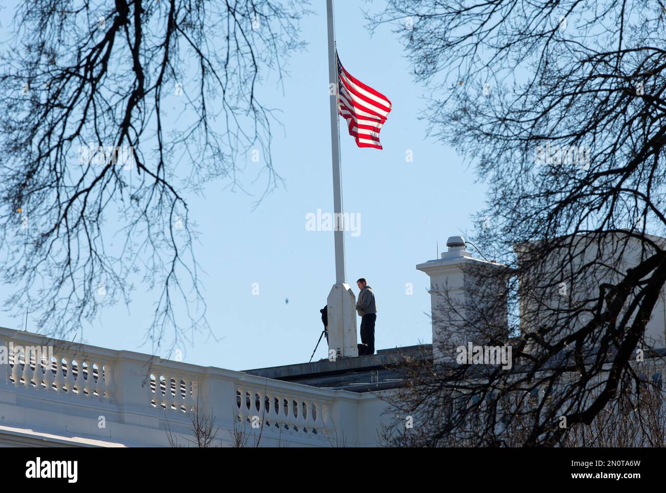 Workers lower the American flag above the White House in Washington ...