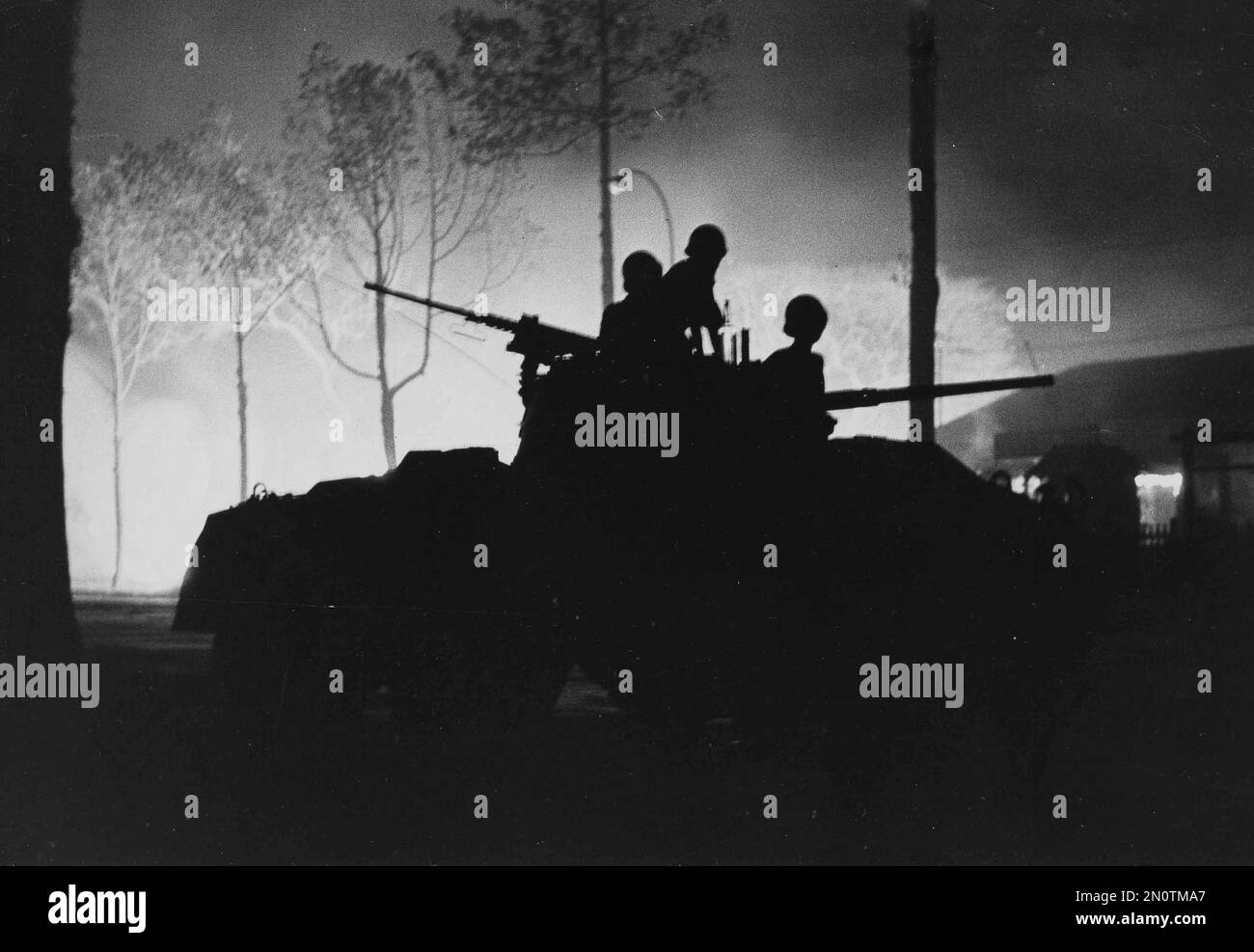 National soldiers on an armored truck are silhouetted against a bright ...