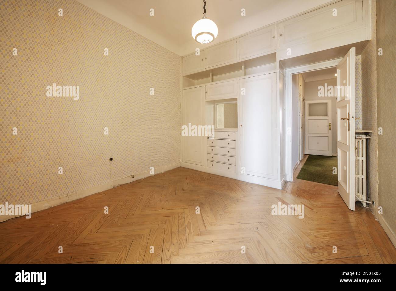 An old empty bedroom with a built in wardrobe that covers an entire ...