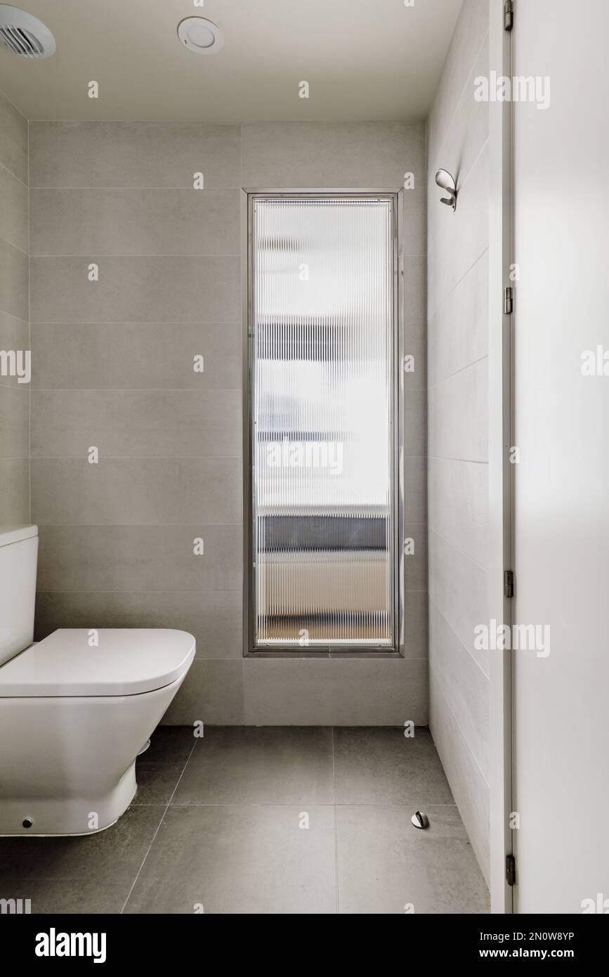 Toilet with toilet next to a rectangular translucent glass skylight ...