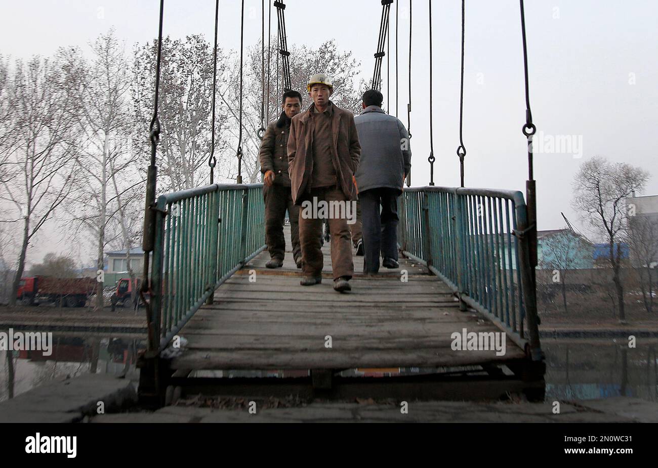 North Korean construction workers walk on a bridge that takes them over ...