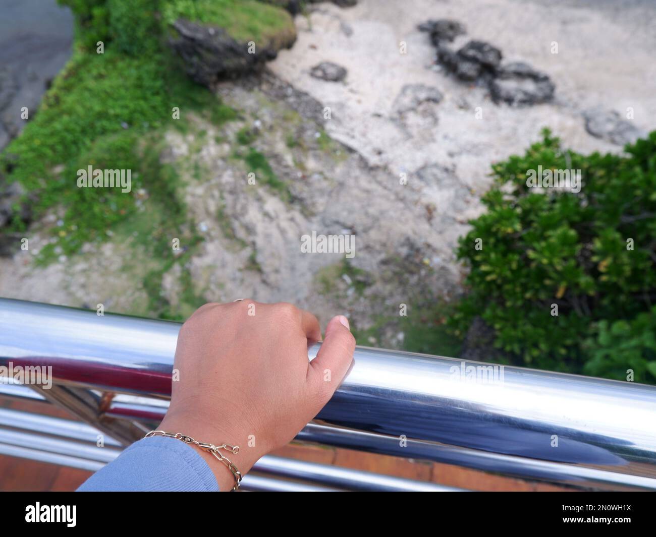 The hand of the woman who is holding the iron barrier of the bridge ...