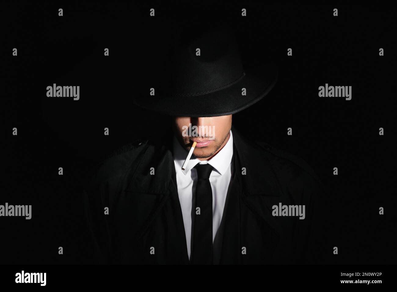 Private detective smoking cigarette on black background Stock Photo - Alamy