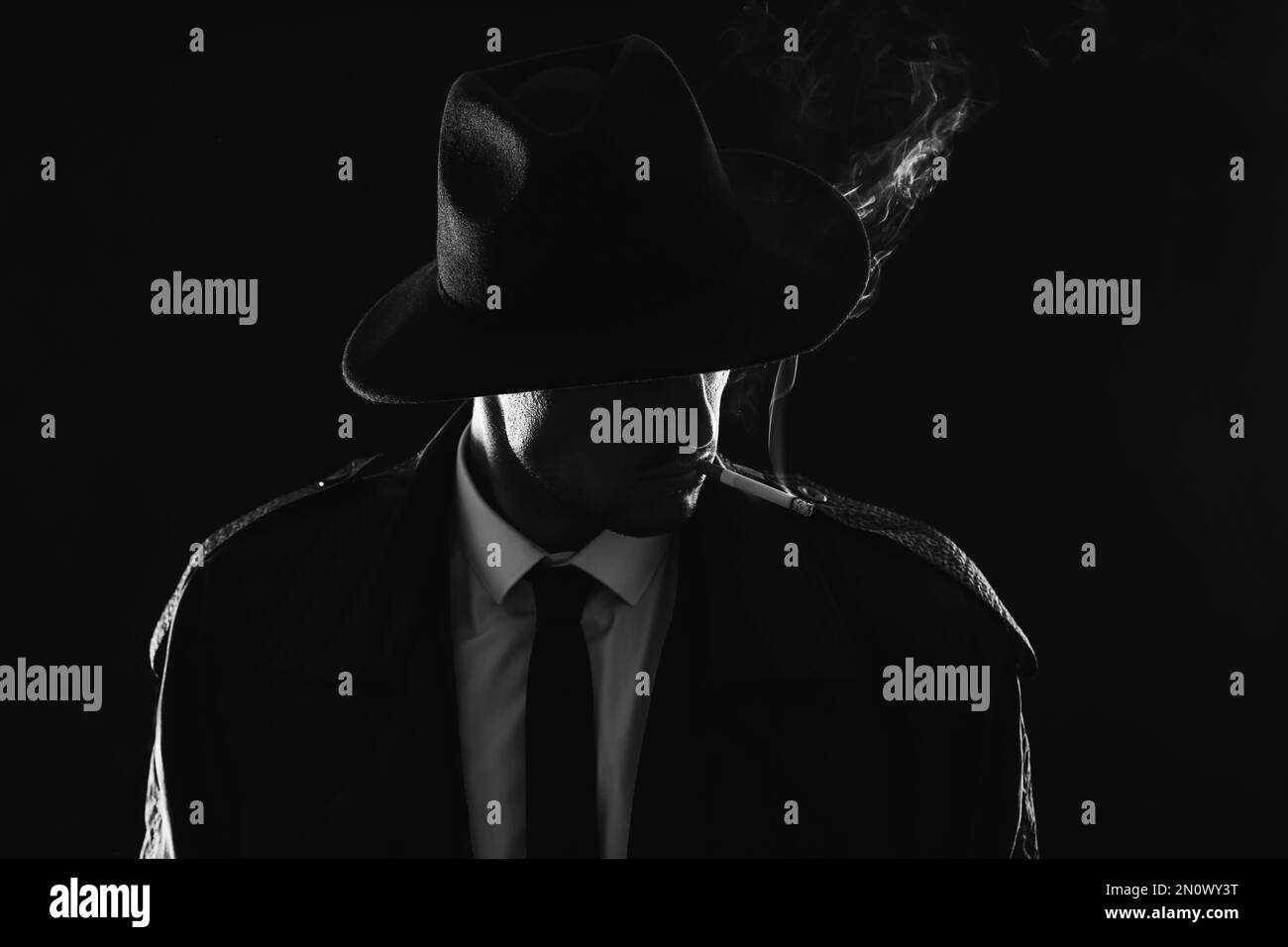 Old fashioned detective smoking cigarette on dark background, black and ...